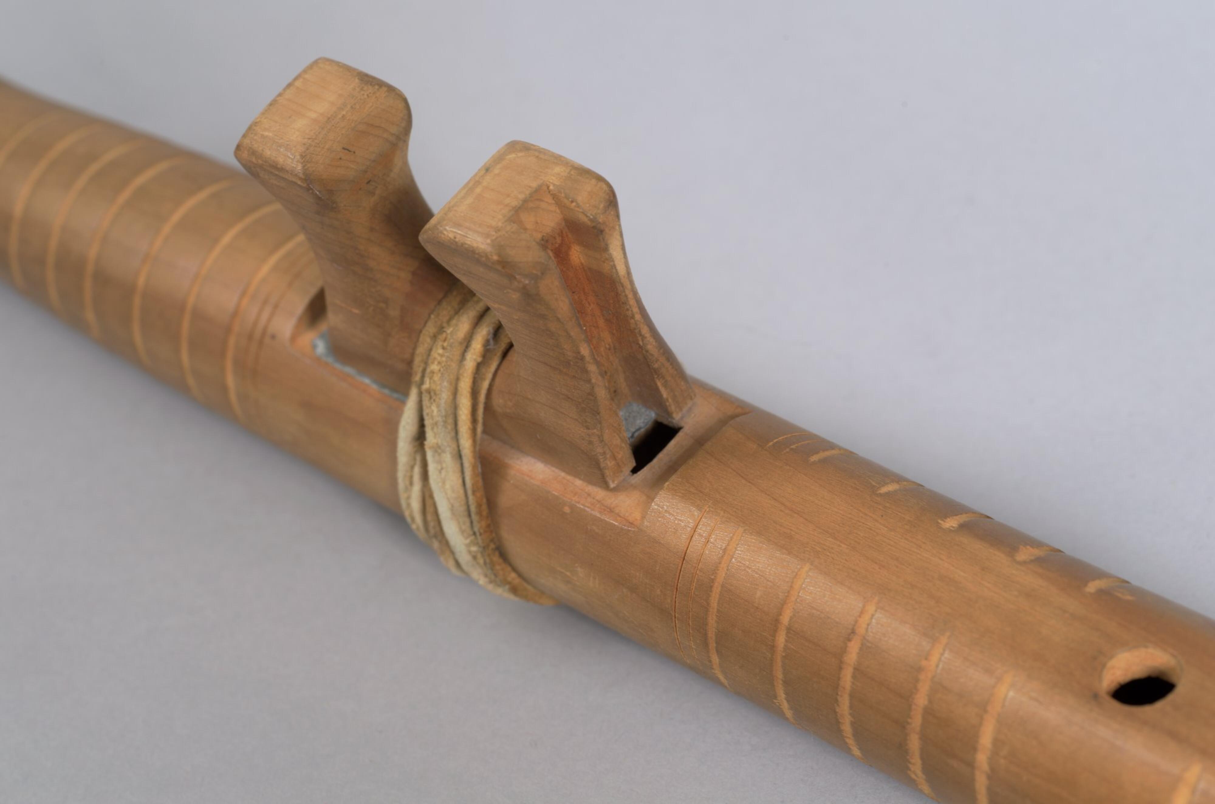 Carved wooden flute with leather straps / Unknown - Gilcrease Museum
